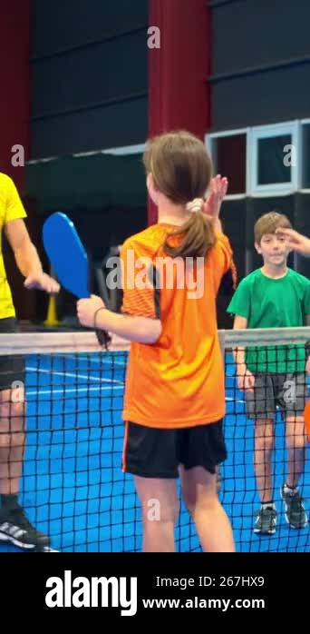 Two adults and two children high-fiving after playing pickleball on a ...