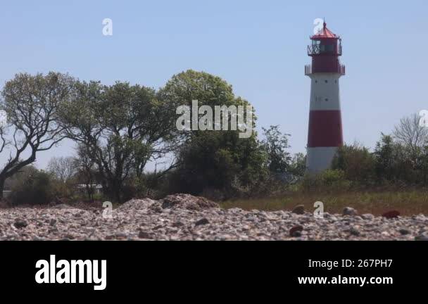 Red and white lighthouse in Pommerby on a cliff overlooking a beach ...