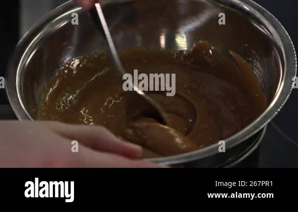stirring caramelized condensed milk in a saucepan, highlighting the ...
