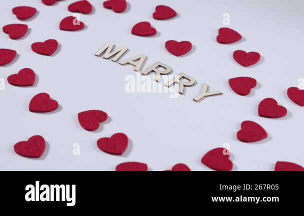 Arranging wooden letters to spell MARRY ME surrounded by red heart ...