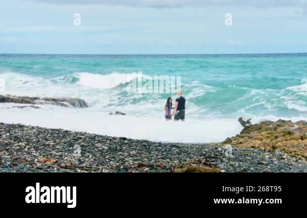 a powerful wave knocked a couple off their feet on a rocky ocean coast ...