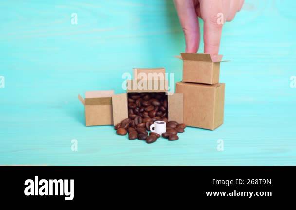 Hand places toy croissants and mini coffee cups into small cardboard ...