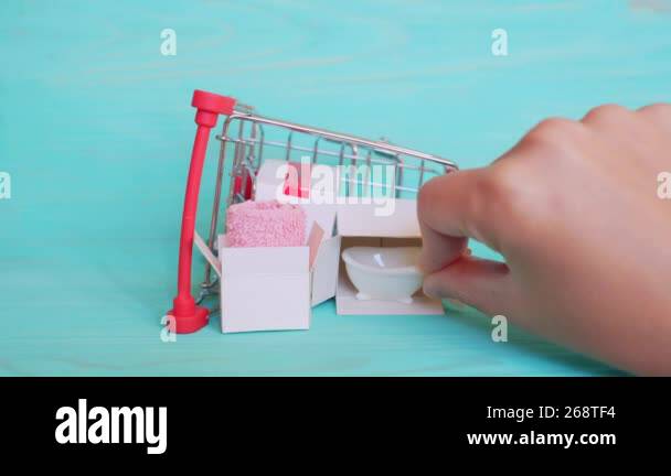 Hand positions a rubber duck on a miniature bathtub next to an ...