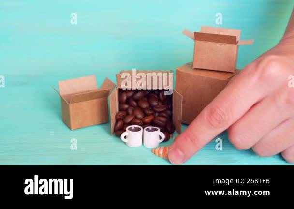 Hand putting miniature coffee cups, croissants, and coffee beans back ...