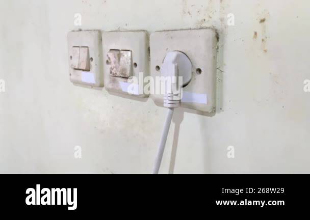Young adult man hand holding and unplug white electrical plug in wall ...