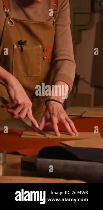 Vertical tilt up shot of dedicated young Caucasian craftswoman in apron ...