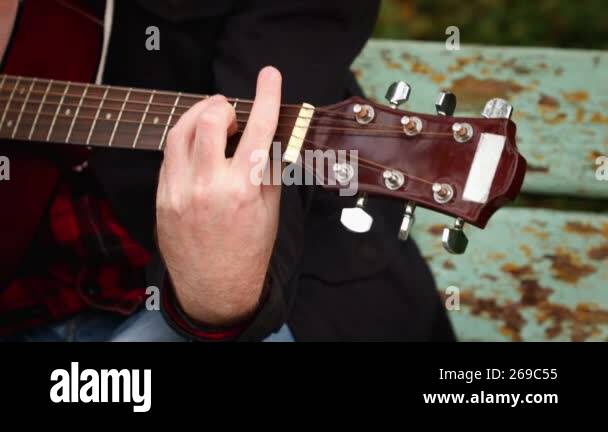 Close up of man's hand clamping a chord on guitar neck. Learning to ...