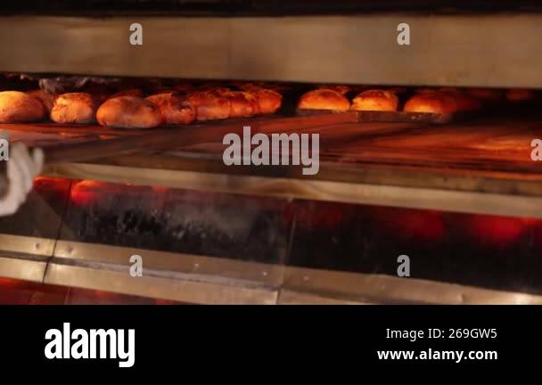 Baker removing golden brown bread from industrial oven Stock Video ...