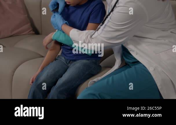 Close-up of caring woman physician adjusting arm sling bandage to child ...