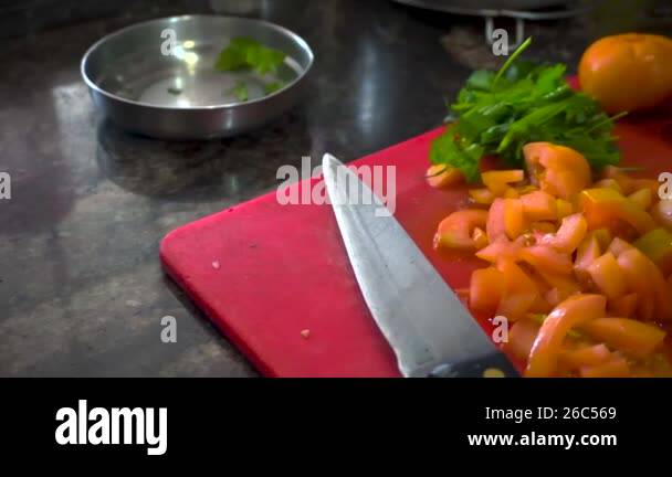 Tabletop view of chopped tomatoes and a chef knife on a chopping board ...