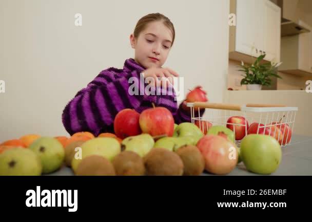 Girl placing apples into basket while organizing fruits. Female sorting ...