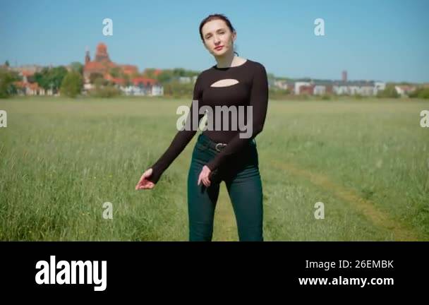 Woman performing graceful dance moves in green field, expressing ...