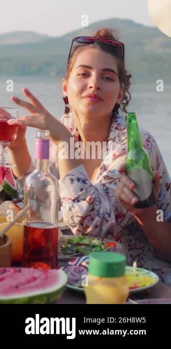 Vertical portrait of smiling young woman with glass of alcohol drink ...