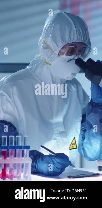 Vertical view of female scientist wearing PPE suit working with ...