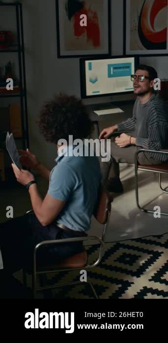 Vertical shot of two colleagues sitting at their own work station ...