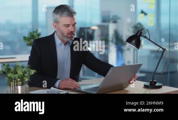 Portrait of handsome successful adult employe using portable laptop ...