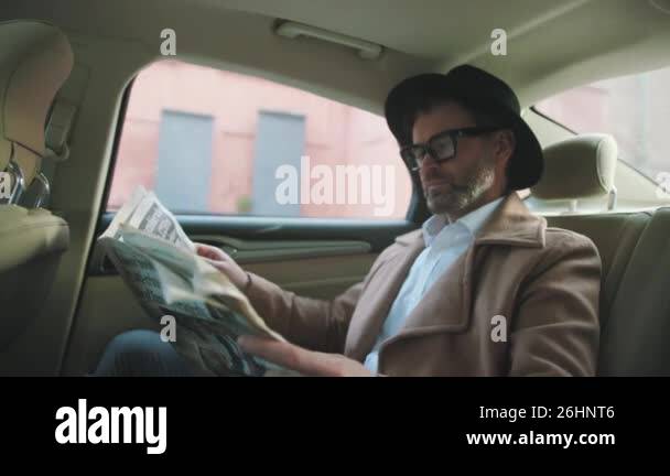 Attractive rich businessman in retro outfit reading a newspaper sitting ...