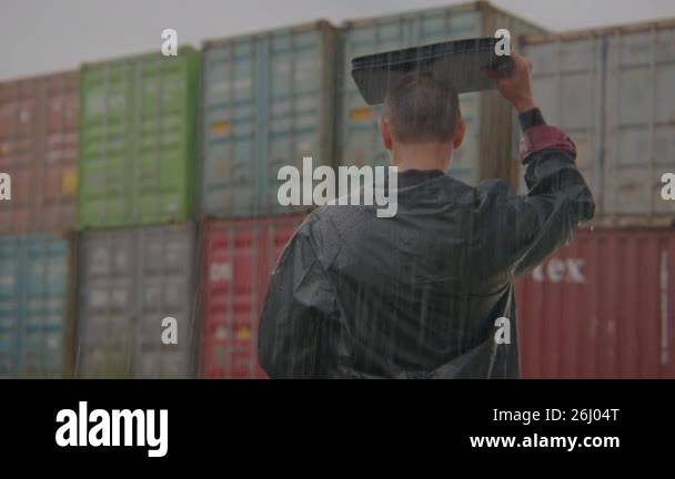 A workers bravely navigating through challenging rainy conditions while managing cargo ...