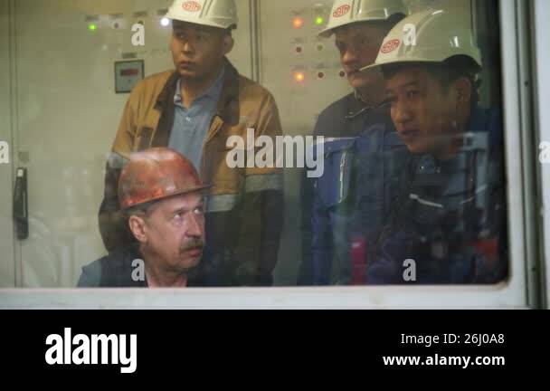 A group of dedicated workers attentively observing the machinerys operations while inside a ...