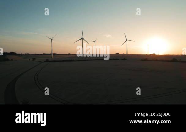 Wind turbines dotting the open landscape at sunset, framed by gentle ...