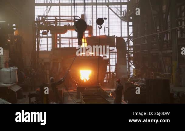 Dynamic scene of molten steel pouring in an industrial foundry, highlighting manufacturing ...