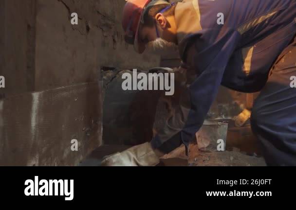 A highly skilled construction worker is meticulously applying cement to ...
