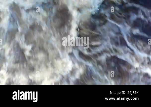 Closer drone shot of a rapid river showing the fast flowing water ...