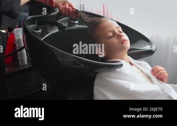 Relaxed girl having hair washed by hairdresser in salon. Anonymous ...