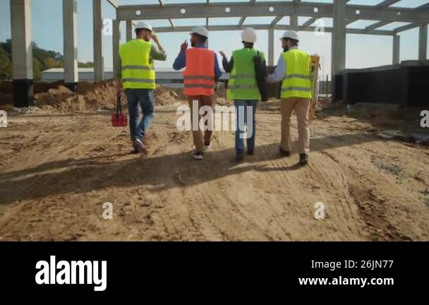 Back shot of young construction workers in high visibility vests and ...