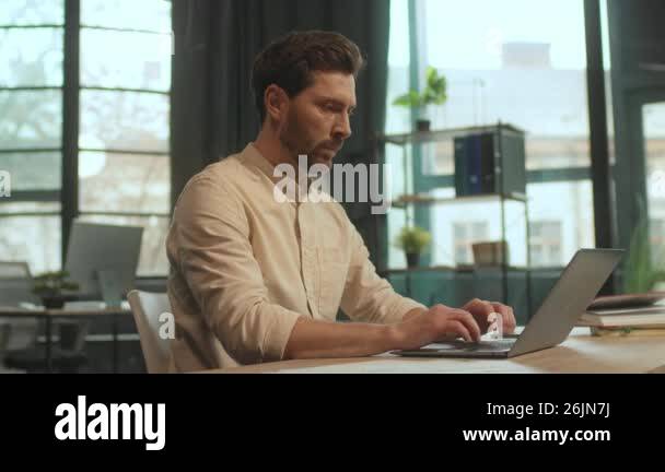 Attractive worker man sitting at desk use laptop typing on keyboard in ...