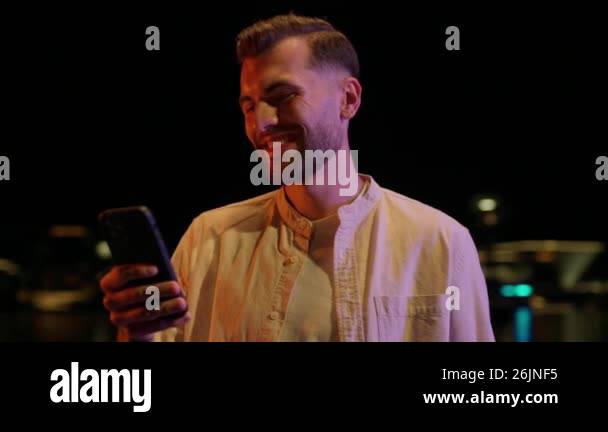 Handsome young man standing scrolls social media uses smartphone at ...