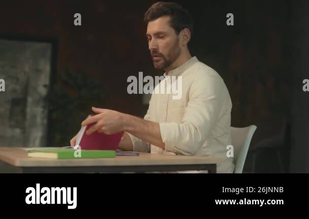 Portrait of young man sitting at desk work with notebook use phone ...