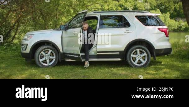 Attractive man getting out of the car and looking around opening the ...