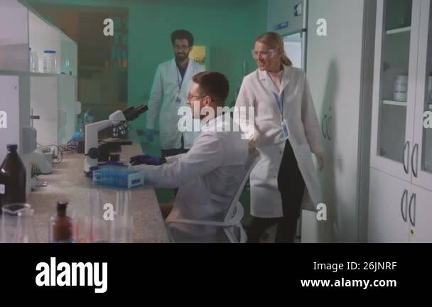 Group of scientists with glasses looking under a microscope in a light ...
