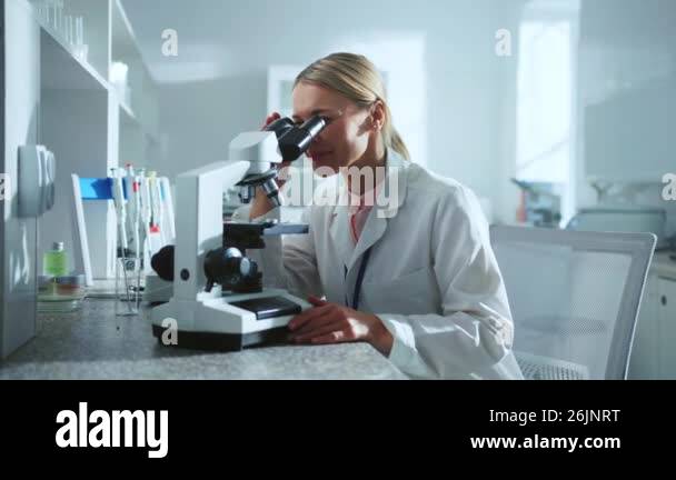 Close up scientist woman looking under the microscope smiling in the ...