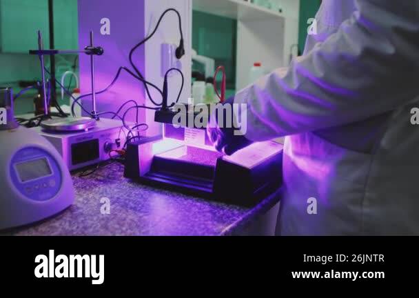 Man scientist with glasses work with ultraviolet lamps in a light ...
