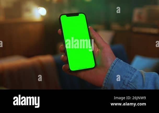 Hands holding using a mobile phone with a vertical green screen. Social media. Smartphone. Mock ...