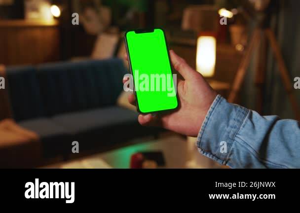Hands using scrolling mobile phone with a vertical green screen. Social media. Smartphone. Mock ...