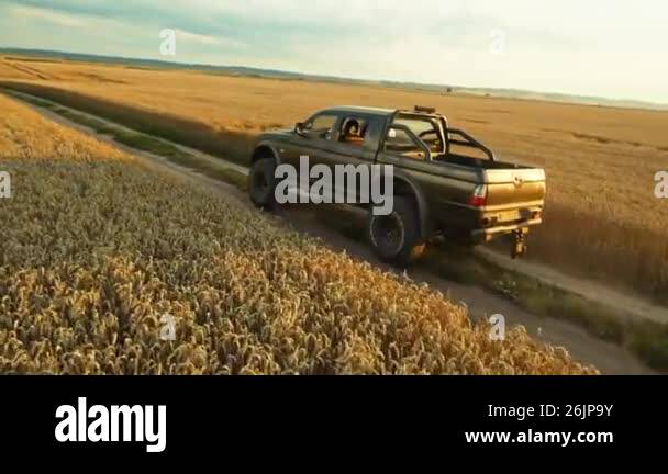 Aerial view of pickup riding by straight ground road through yellow ...