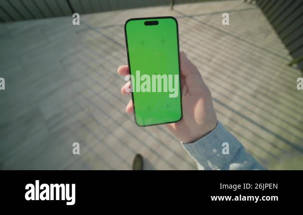 Shot of man hands holding vertically phone with green screen walking ...
