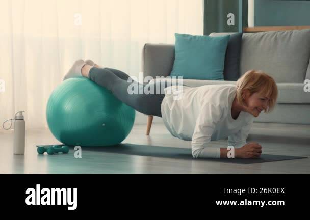 An elderly woman performs an exercise routine using a stability ball in ...