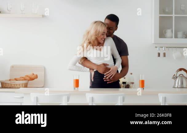 A married couple enjoys intimate bonding in their stylish kitchen ...