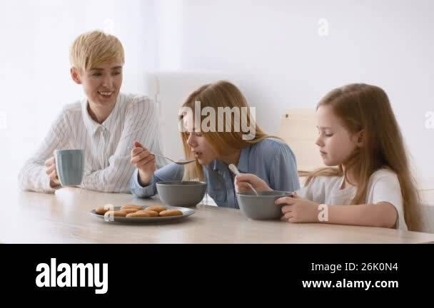 A family gathers around the kitchen table to enjoy breakfast, sharing ...