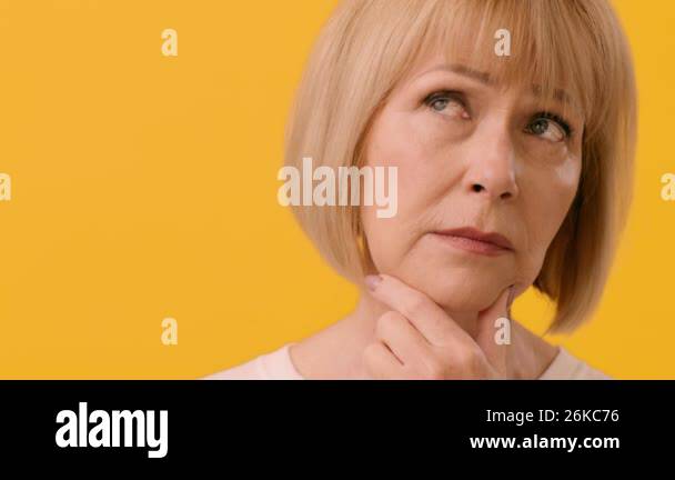 A senior woman with a bob haircut appears deep in thought, resting her ...