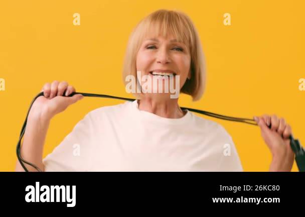 A cheerful elderly woman with a bob haircut is smiling as she holds a ...