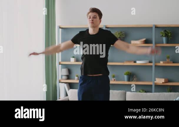 A sporty young man engages in a workout routine at home, demonstrating ...