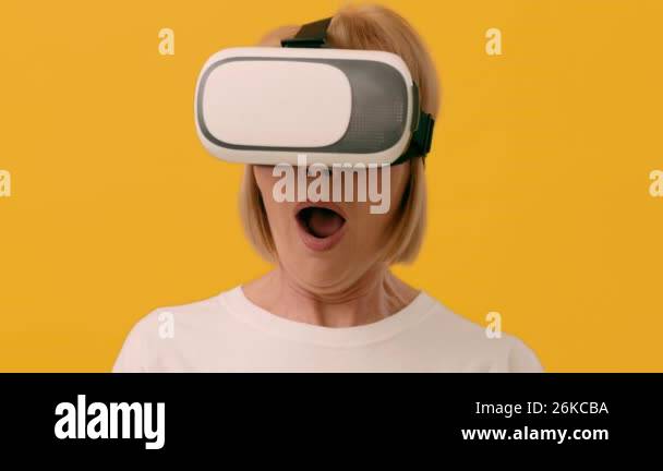 A woman shows enthusiasm while wearing a virtual reality headset, fully ...