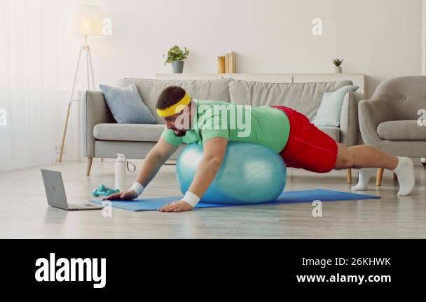 A young man engages in a home workout on a stability ball, focusing on ...