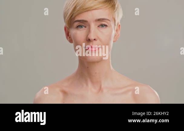 A Caucasian woman in her 50s is applying skincare products on her face ...