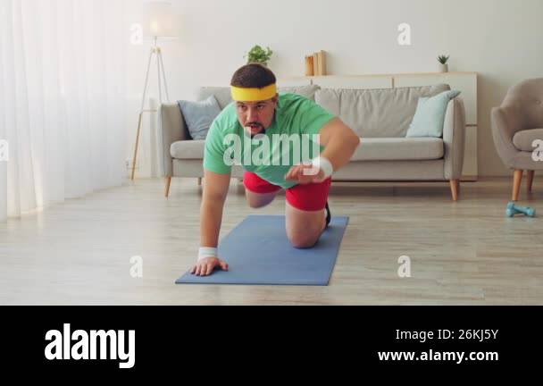 A man performing an exercise routine in his living room. He is dressed ...